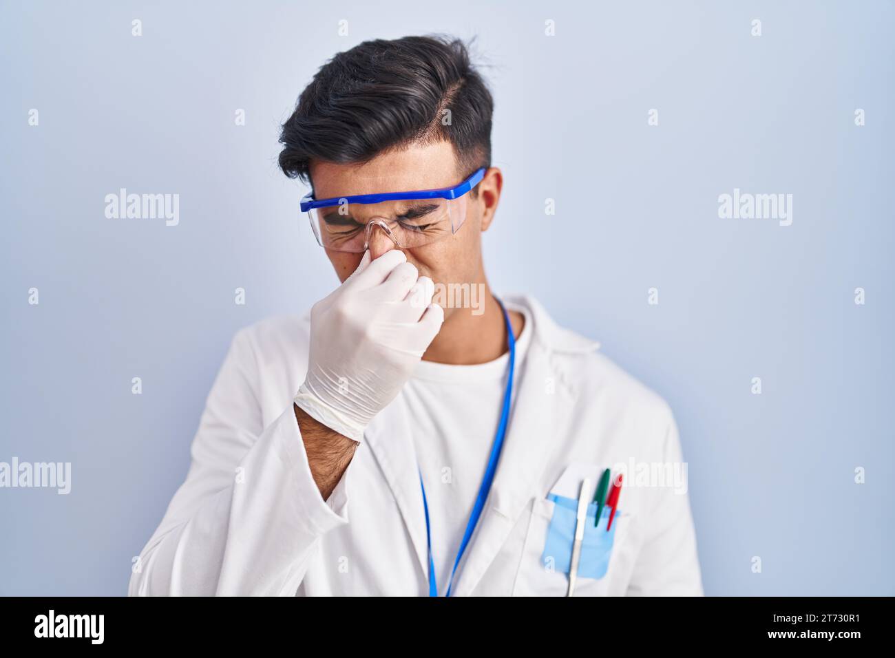 Hispanic man working as scientist smelling something stinky and ...