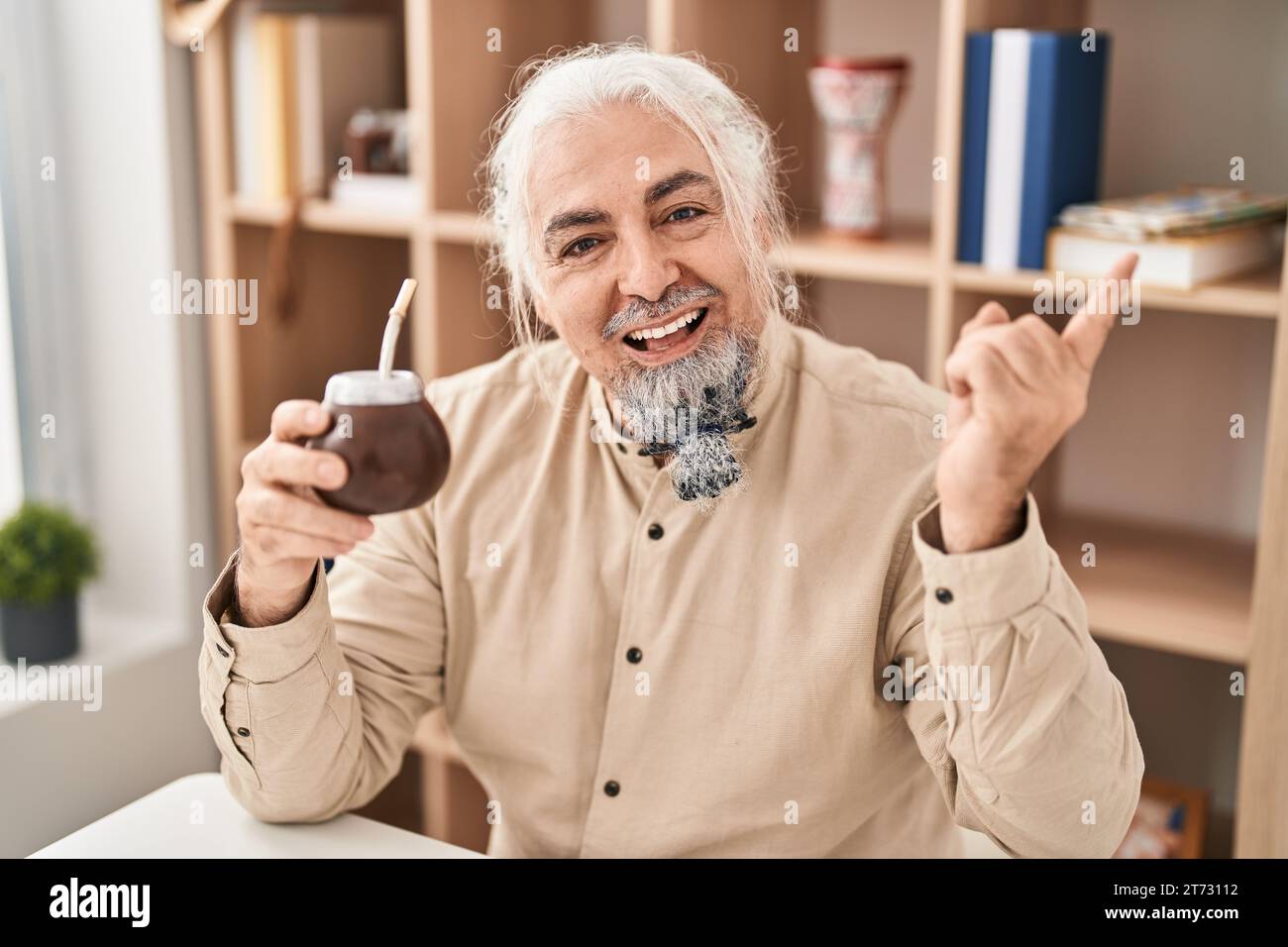 Middle age man with grey hair drinking mate infusion smiling happy ...