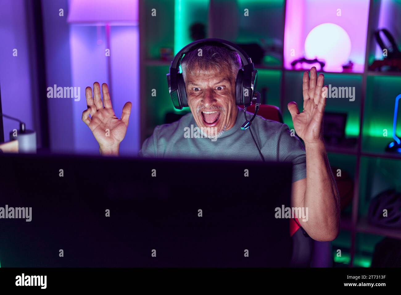 Middle age grey-haired man streamer playing video game using computer ...