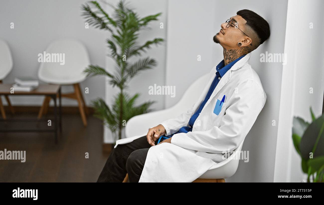 Exhausted young latin doctor in white coat, sitting stressed in the ...