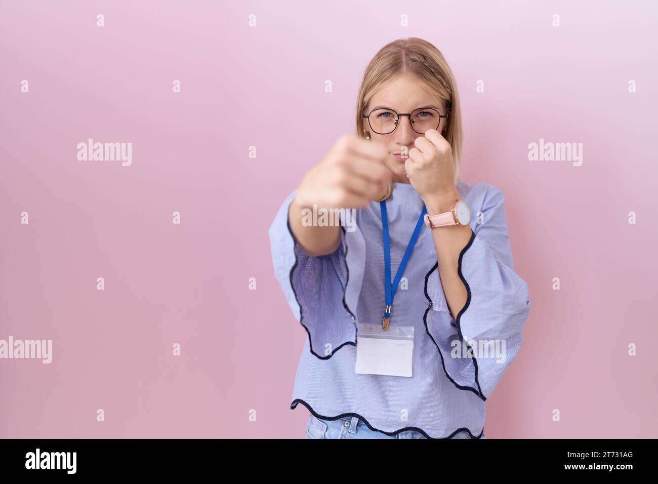 Young caucasian business woman wearing id card punching fist to fight ...