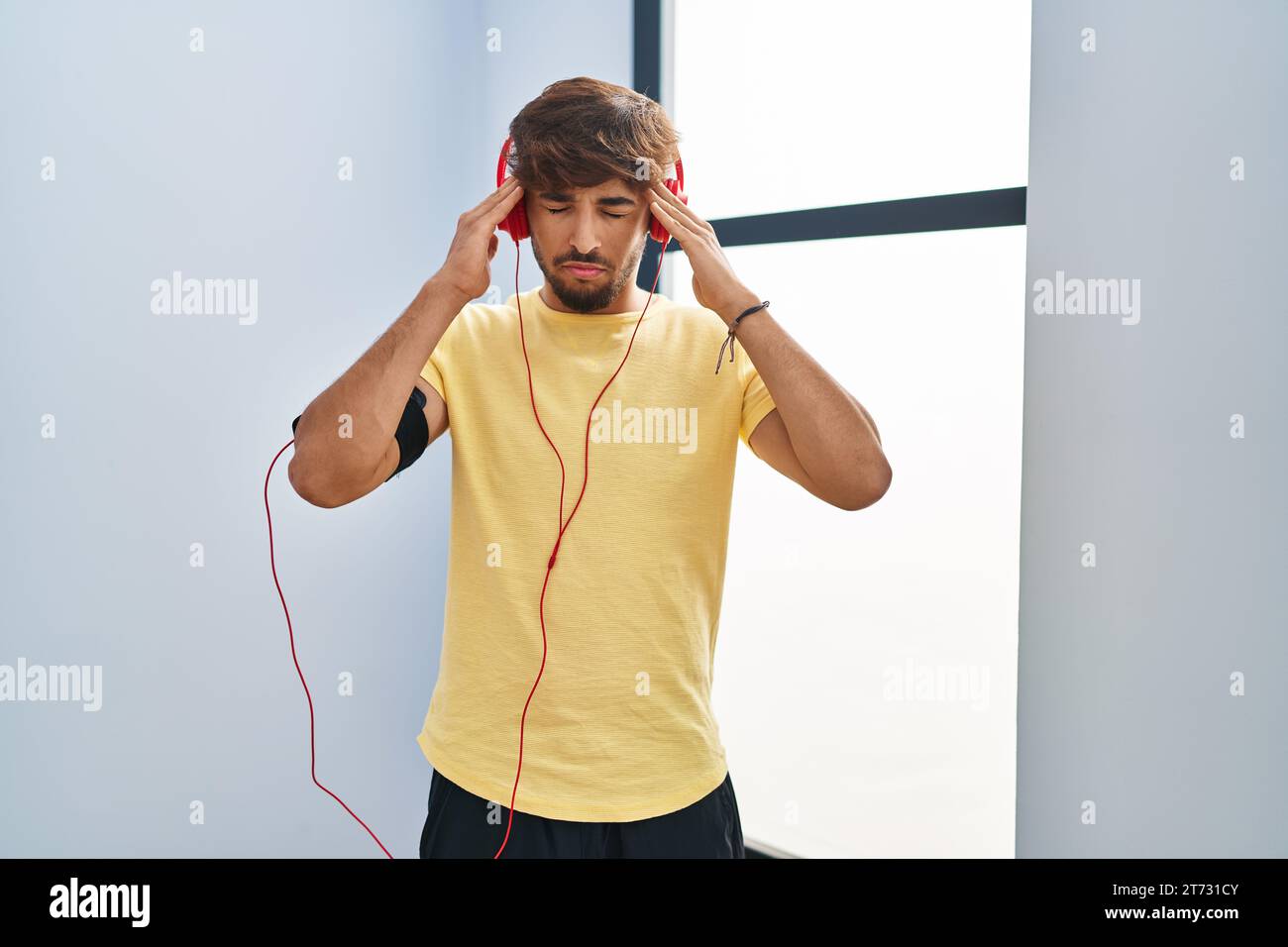 Arab man with beard wearing sportswear and headphones depressed and ...