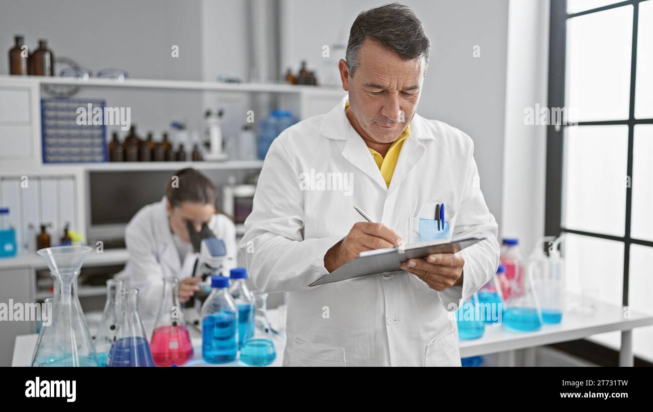 Male and female scientists working together in lab, serious ...