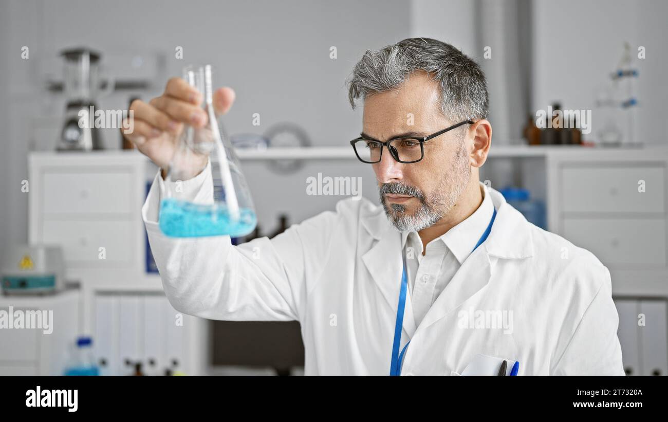 Attractive young hispanic man, grey-haired chemist, concentrating on ...