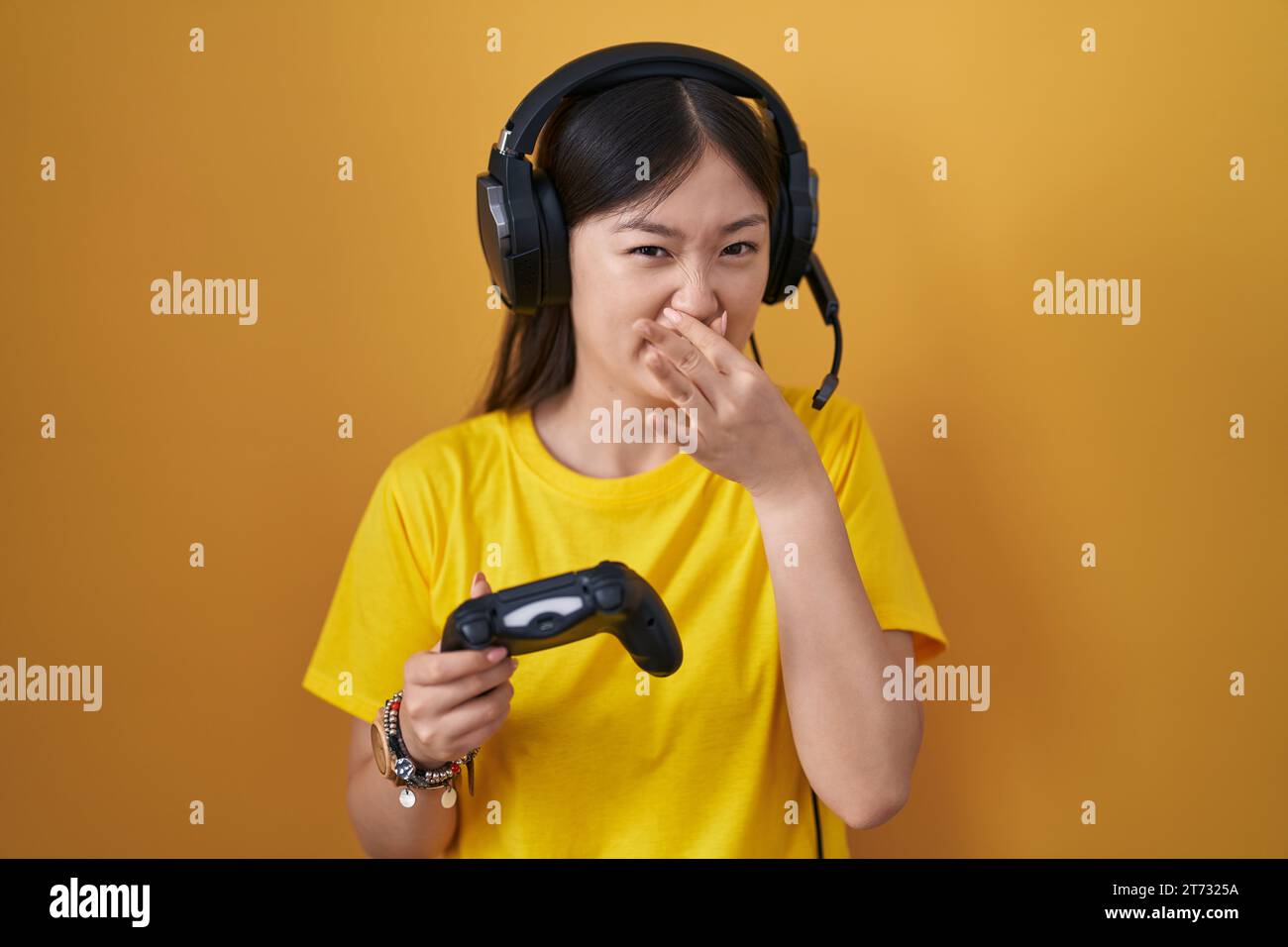 Chinese young woman playing video game holding controller smelling ...