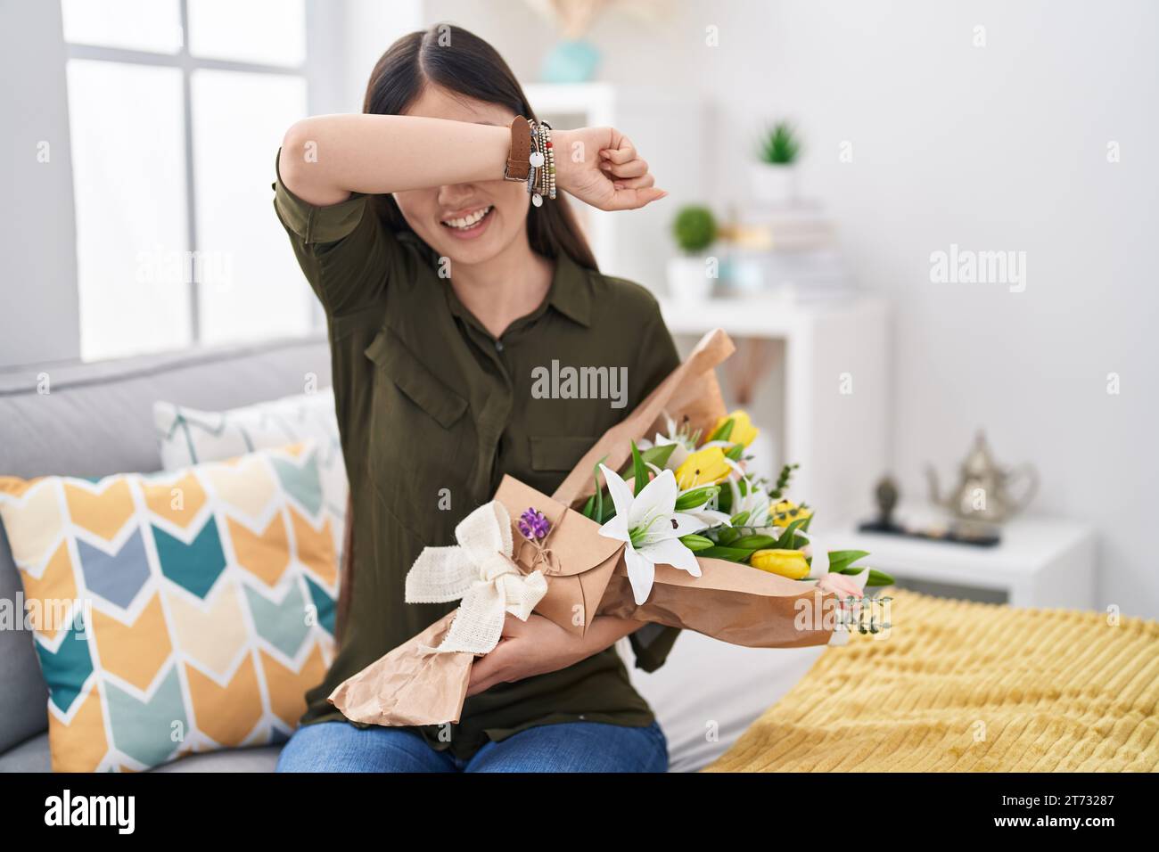 Chinese young woman holding bouquet of white flowers smiling cheerful ...