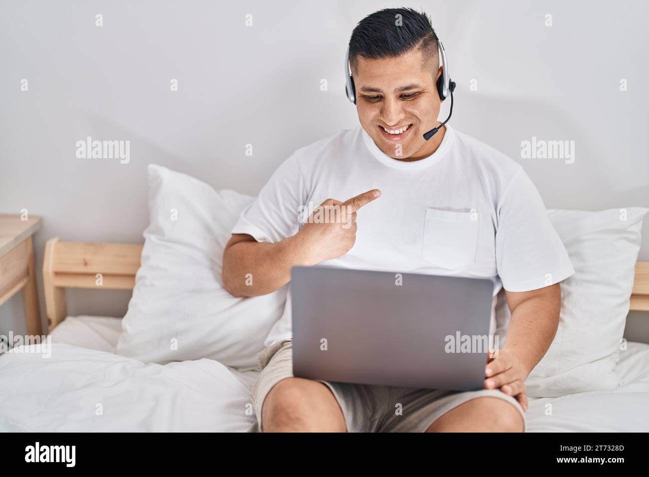 Hispanic young man using computer laptop on the bed smiling happy ...
