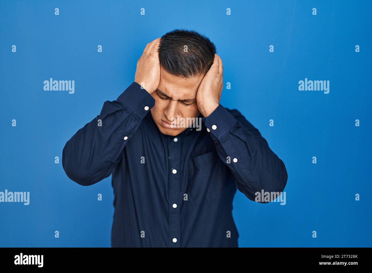 Hispanic young man standing over blue background suffering from ...