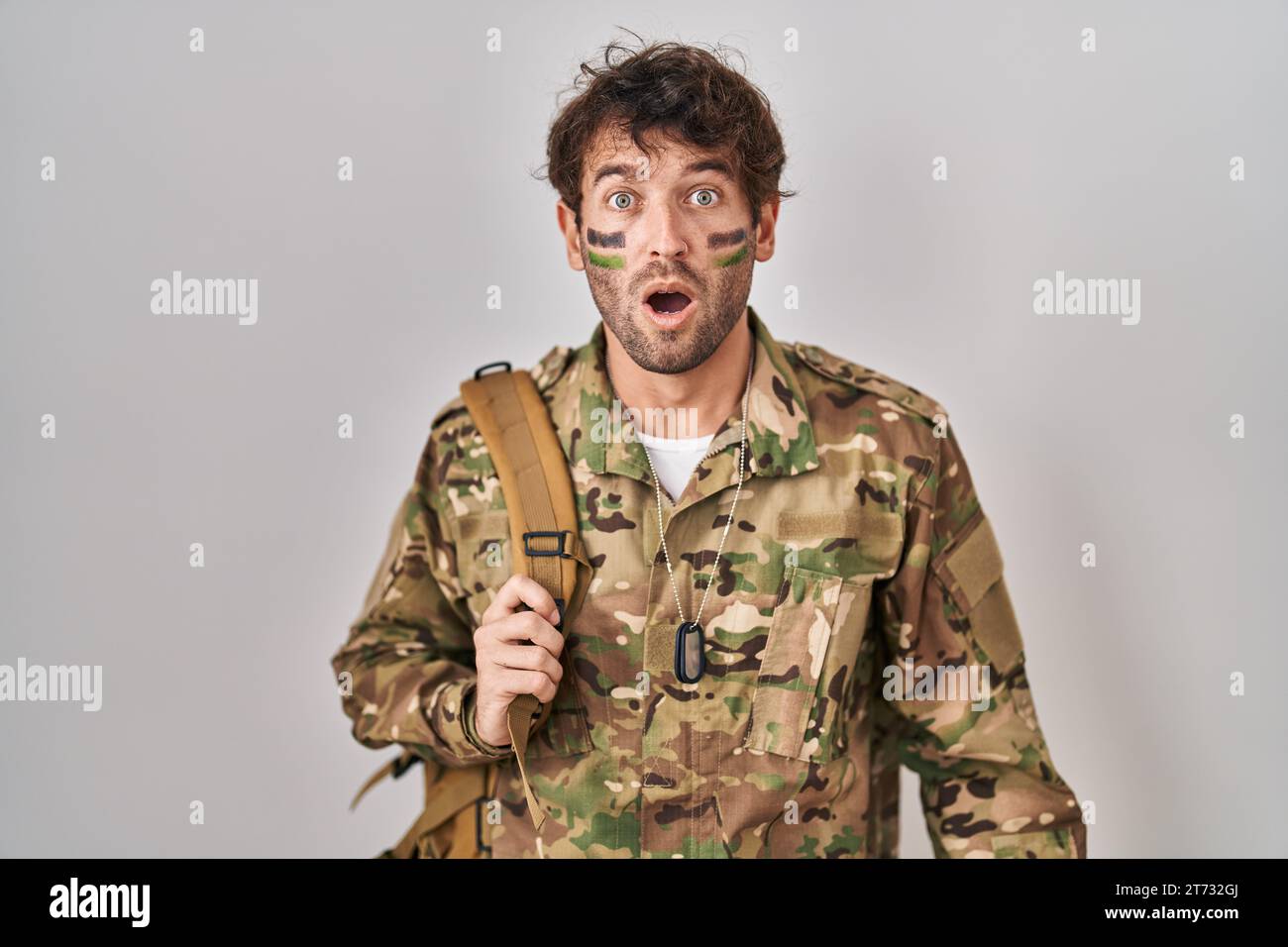 Hispanic young man wearing camouflage army uniform in shock face ...