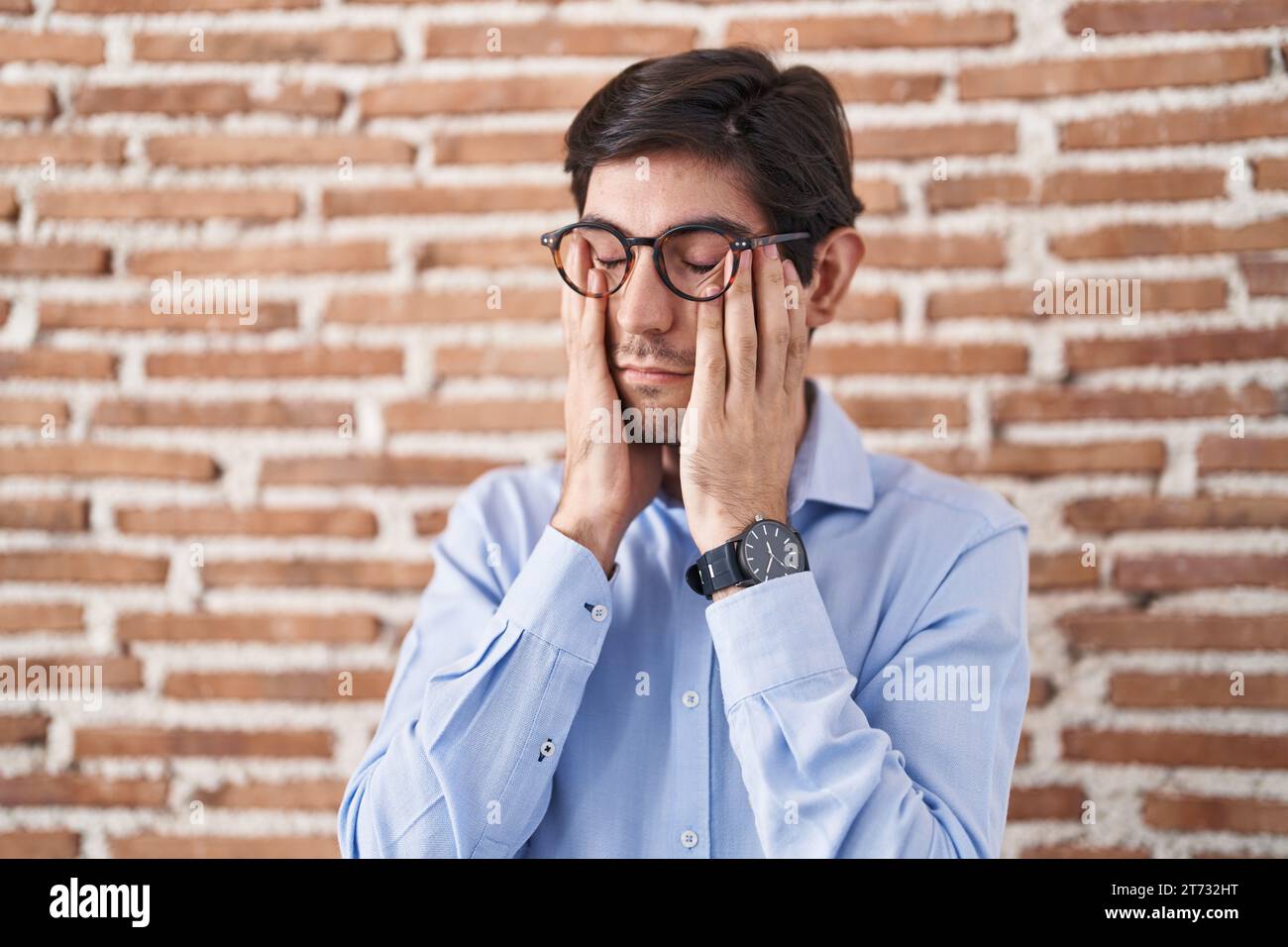 Young hispanic man standing over brick wall background with sad ...