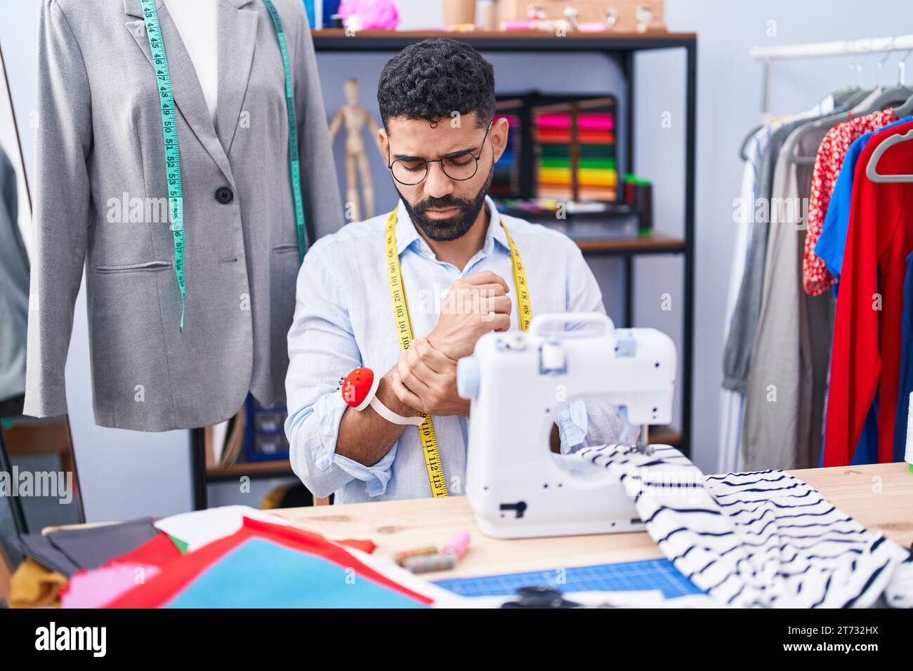 Young arab man tailor stressed using sewing machine at tailor shop ...