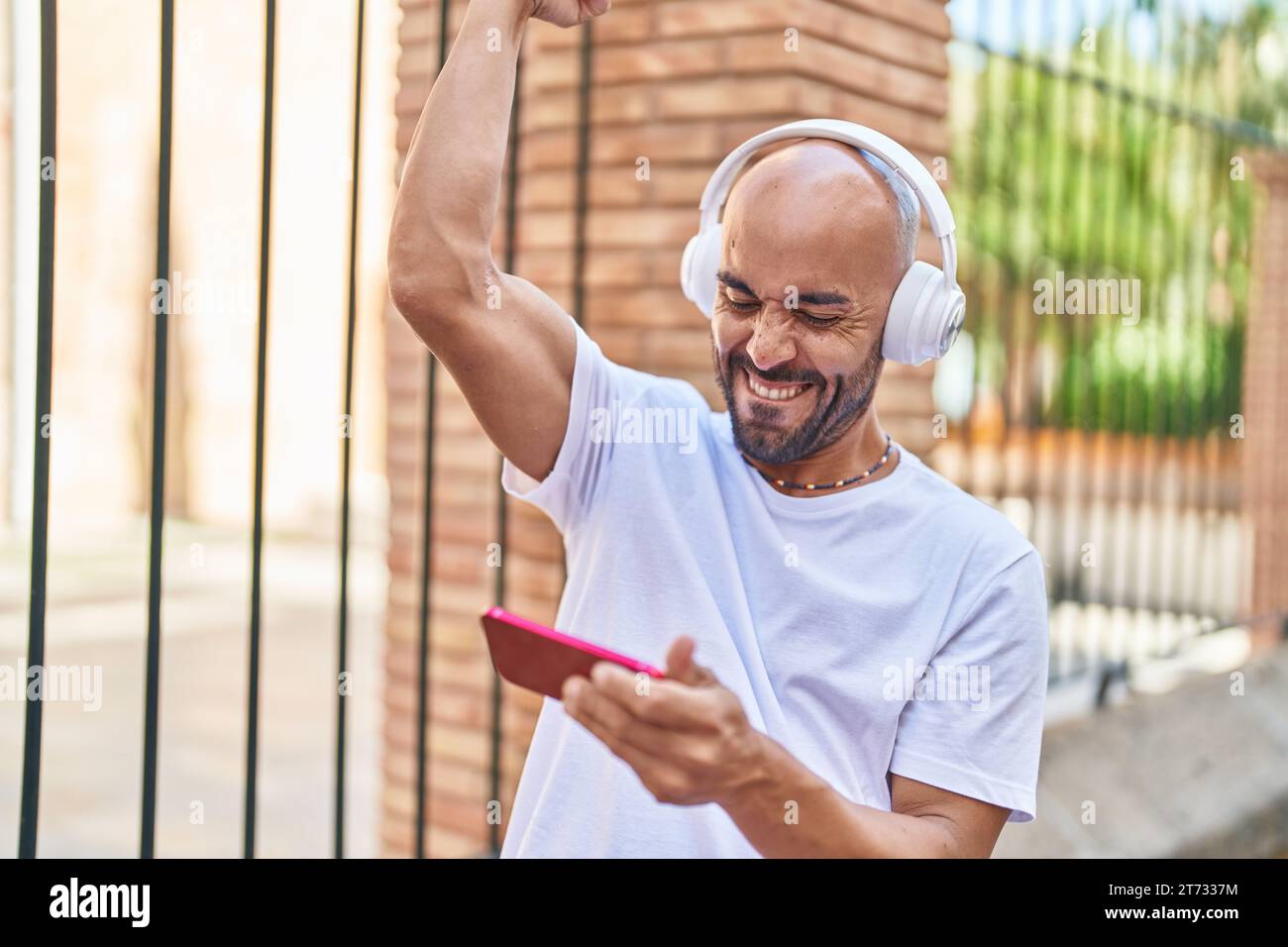 Young bald man smiling confident playing video game at street Stock ...