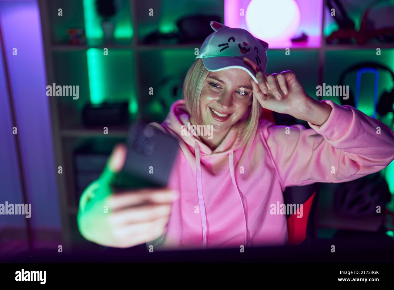 Young blonde woman streamer make selfie by smarpthone at gaming room ...