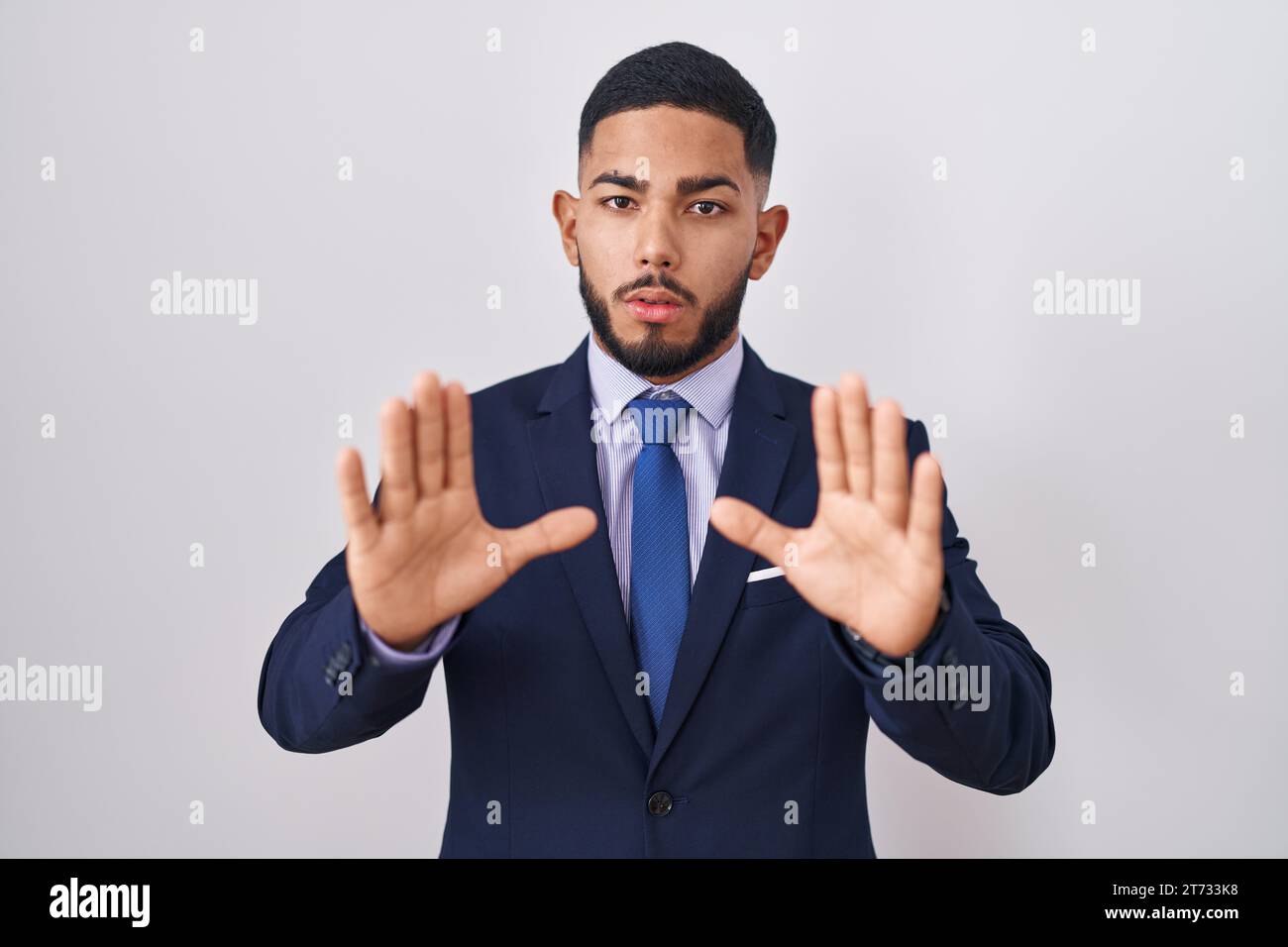 Young hispanic man wearing business suit and tie moving away hands ...
