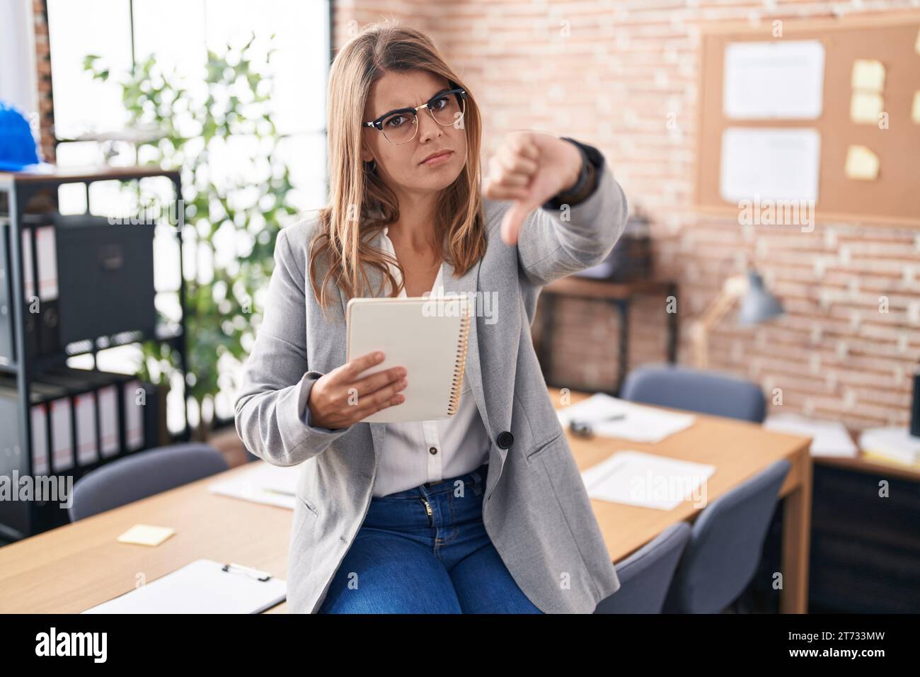 Young hispanic woman working at the office wearing glasses looking ...