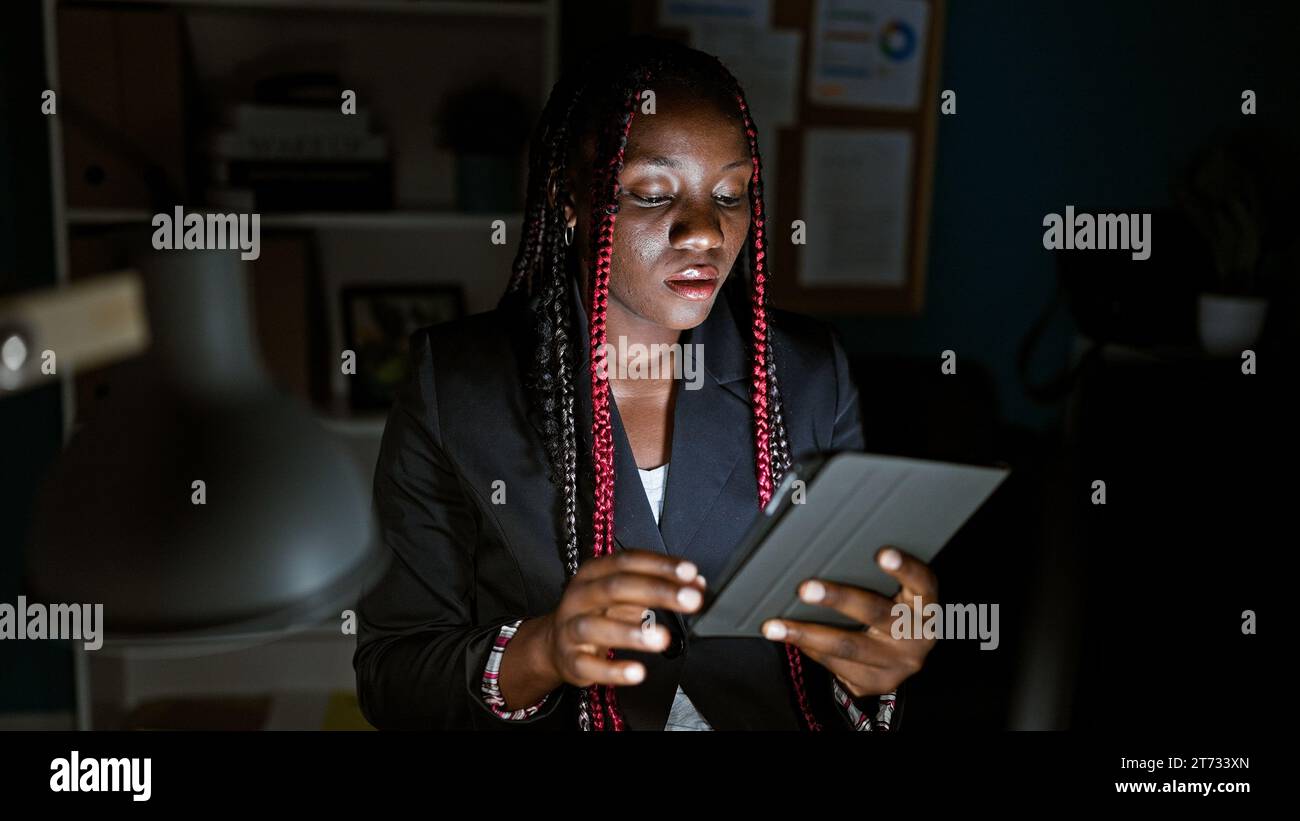 Focused african american woman worker at office, monitors aglow, braids ...