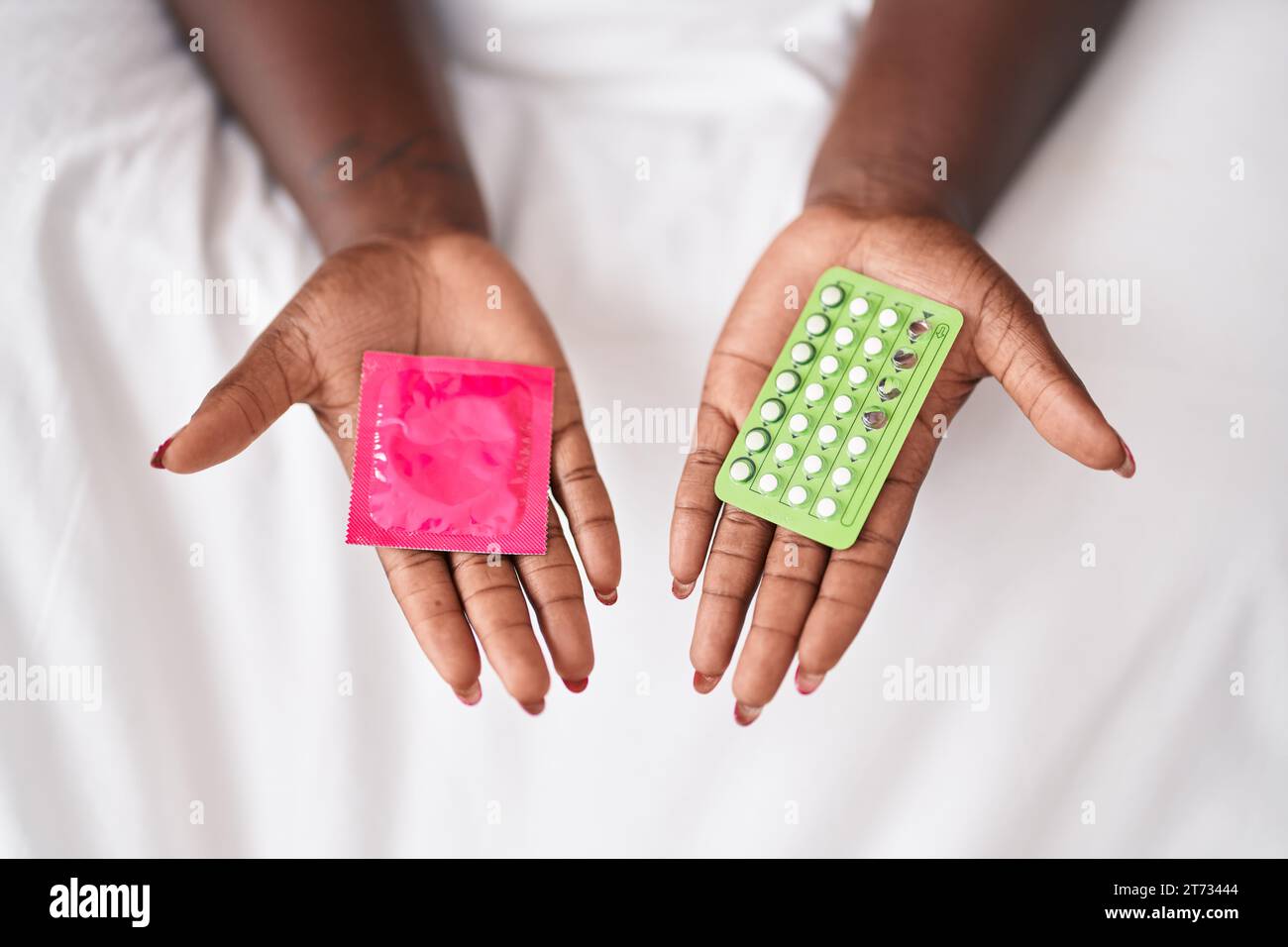 African american woman holding condom and birth control pills at ...