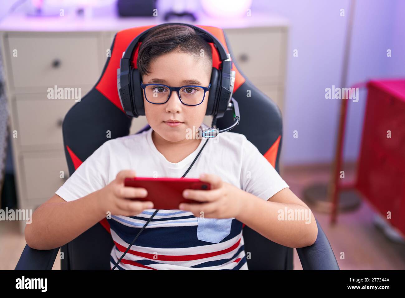 Adorable hispanic boy streamer playing video game using smartphone at ...