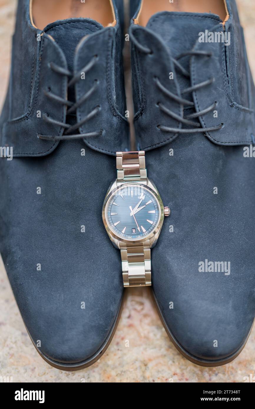 Man watch lies on blue men lace-up shoes standing on a marble floor ...