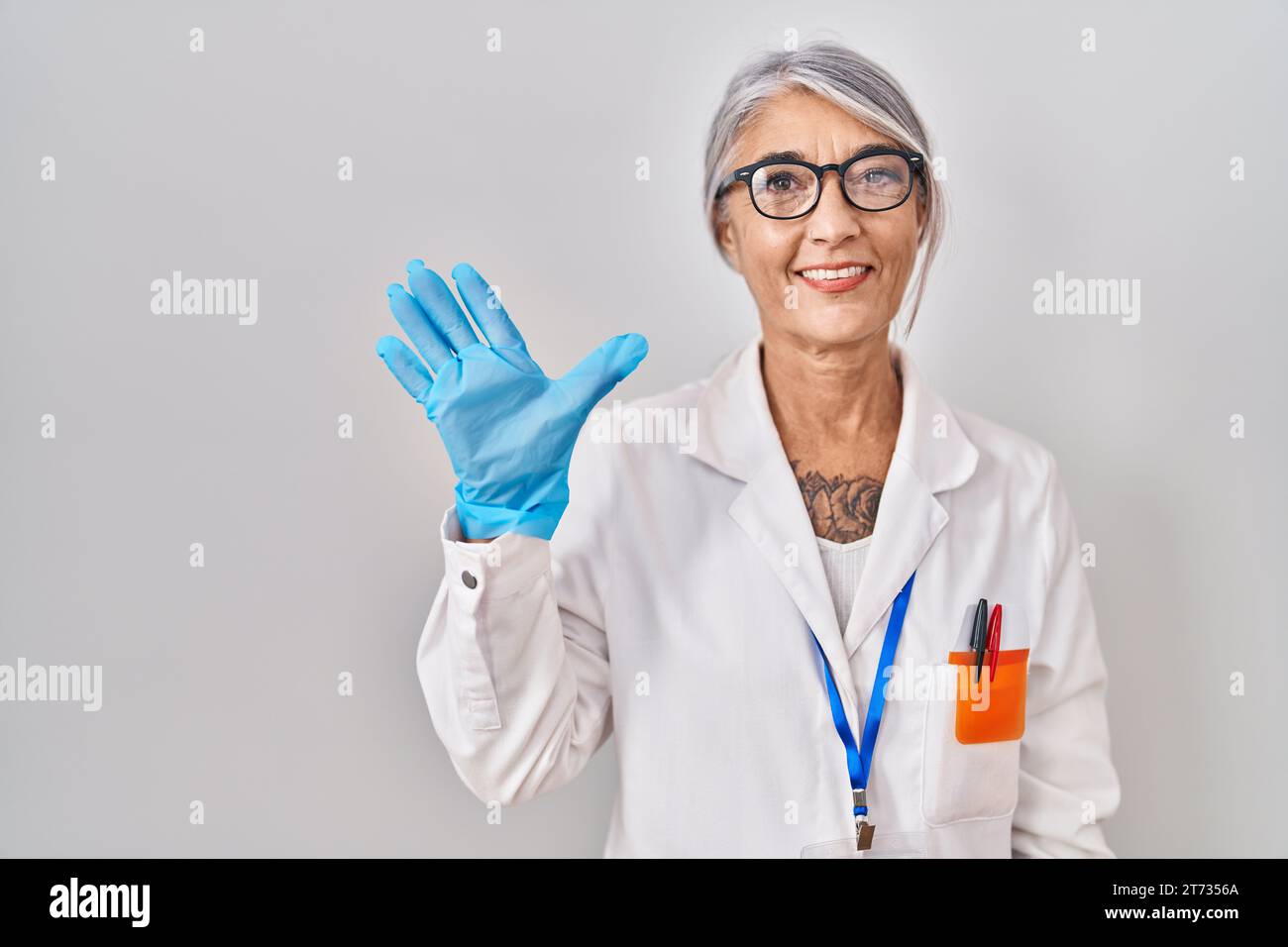 Middle age woman with grey hair wearing scientist robe showing and ...