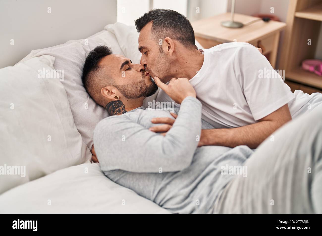 Two men couple lying on bed hugging each other kissing at bedroom Stock Photo - Alamy