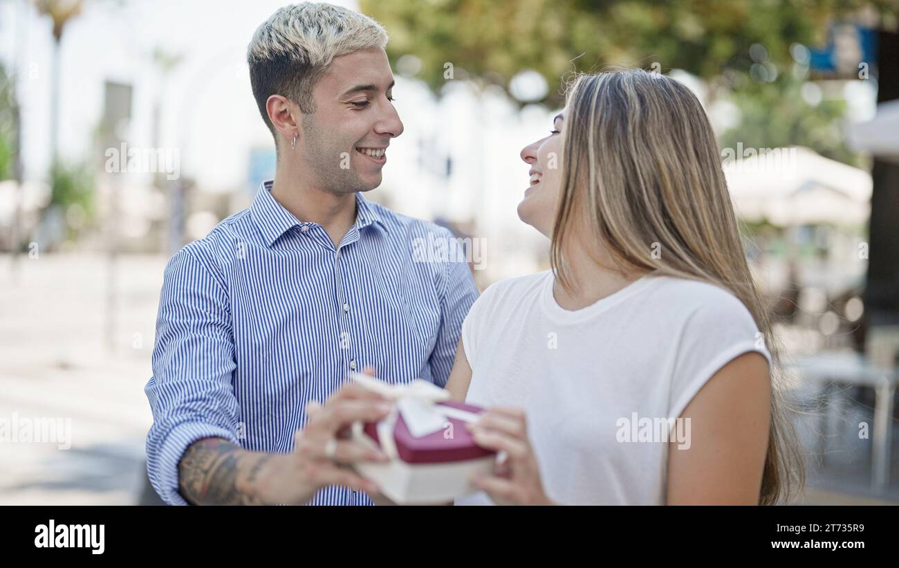 Beautiful couple surprise with heart gift box smiling at street Stock ...