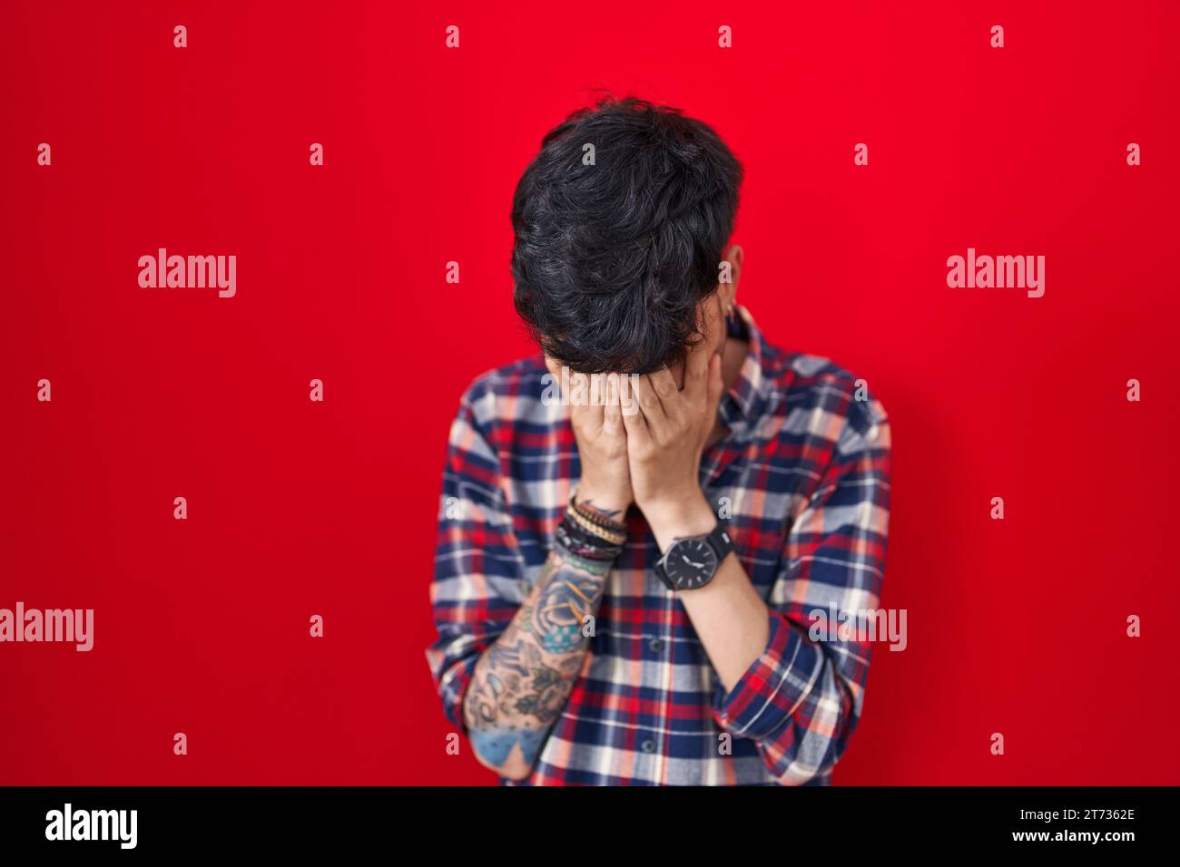 Young hispanic man with beard standing over red background with sad ...