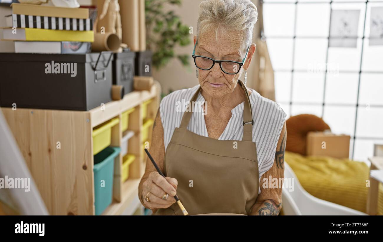 Mature, grey-haired female artist fully immersed in her art, diligently ...