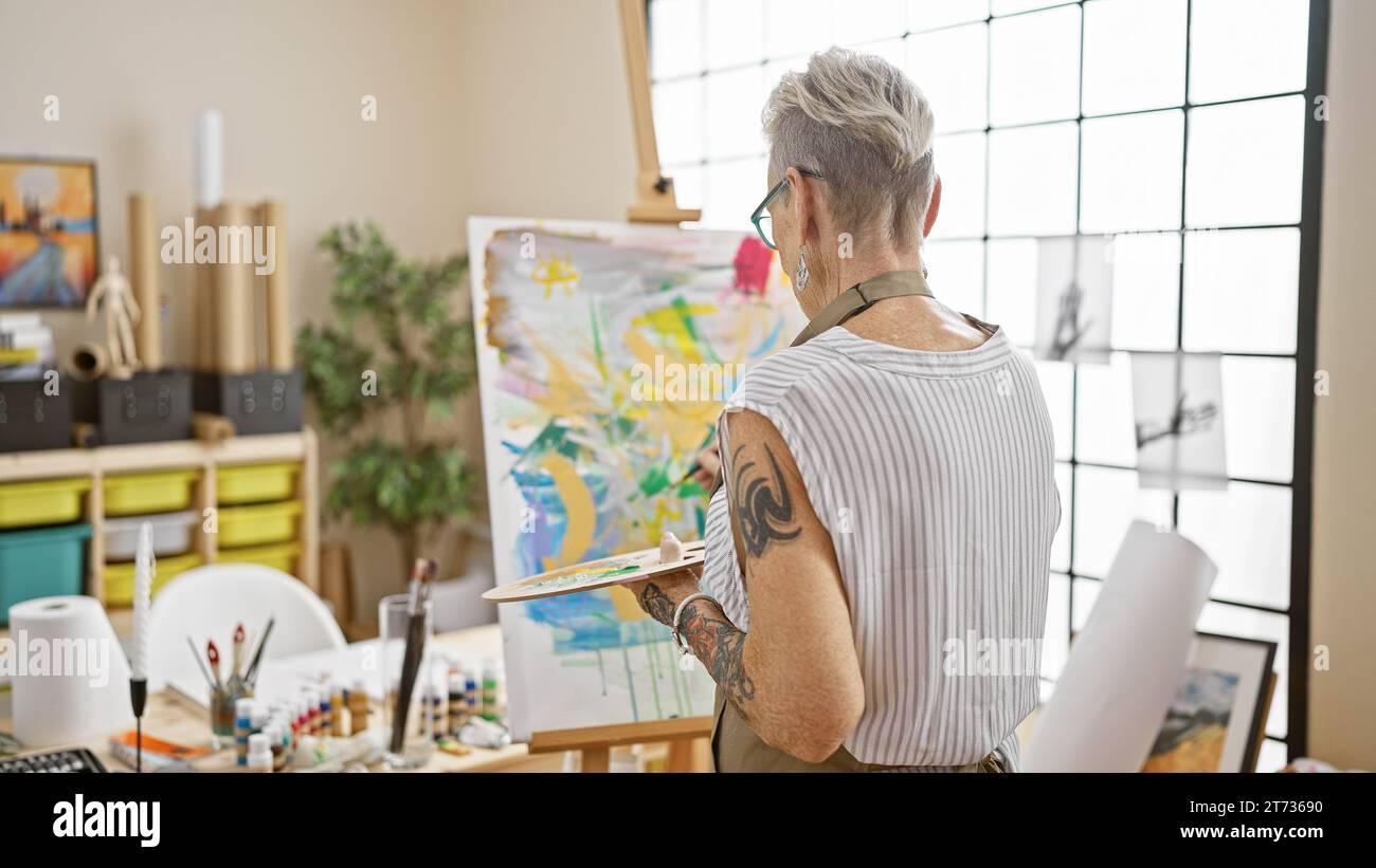 Mature grey-haired woman artist passionately drawing backwards, lost in ...