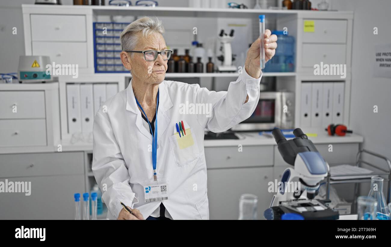 Grey-haired senior woman scientist working and measuring liquid in test ...