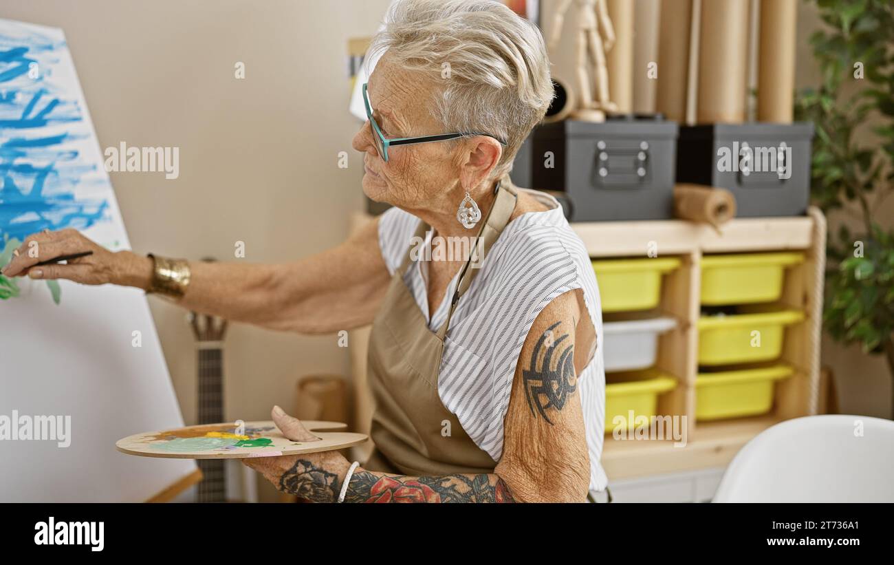 Mature, grey-haired female artist fully immersed in her art, diligently ...