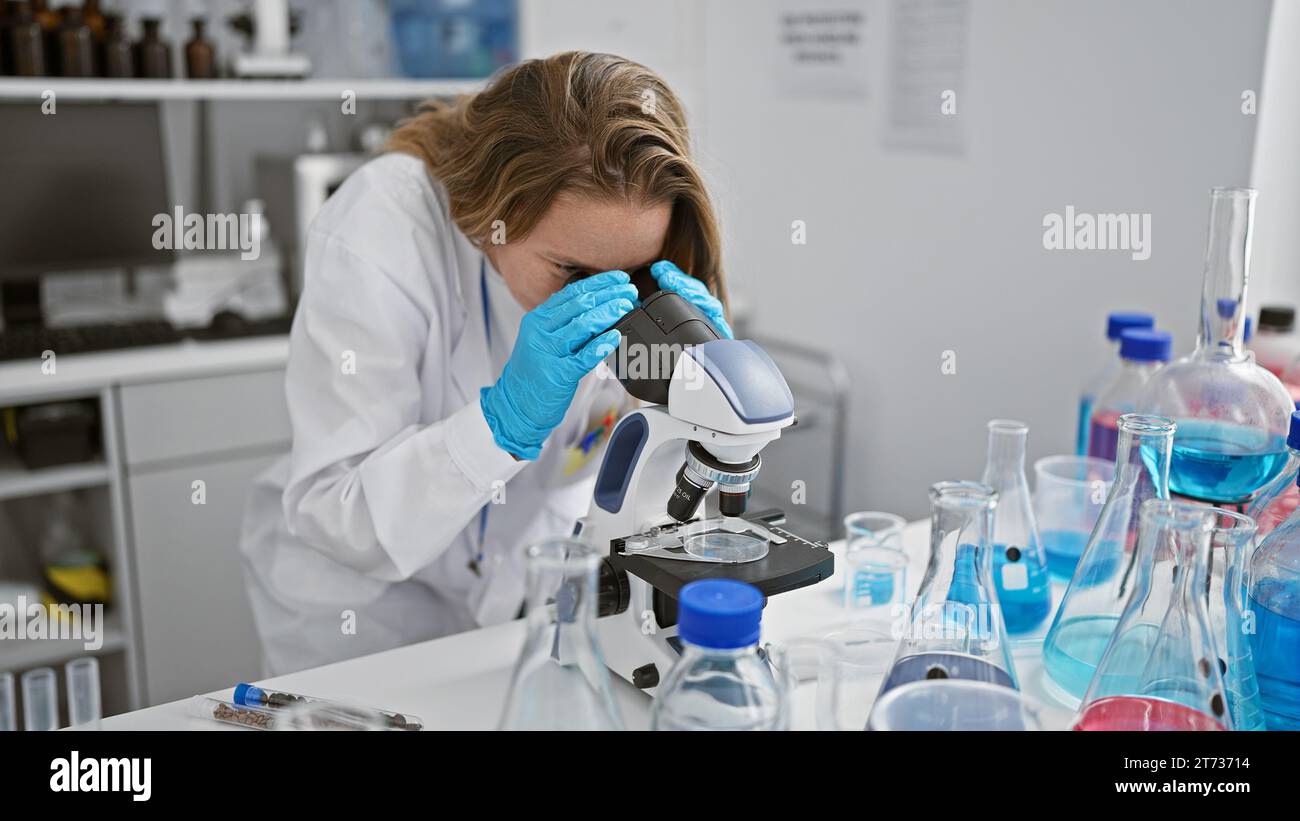Attractive, focused blonde young woman scientist engrossed in her ...