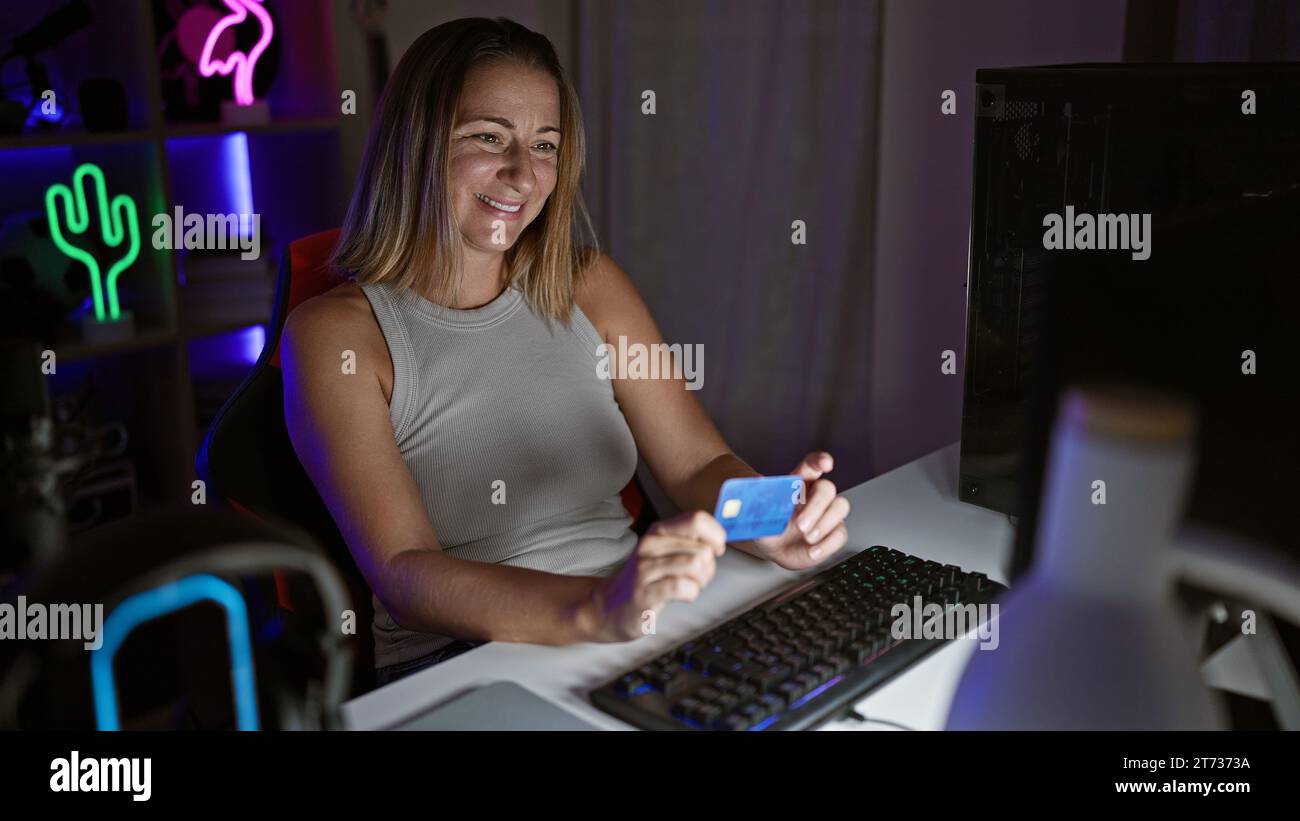 Vibrant, young blonde streamer girl live-streaming gaming session from ...