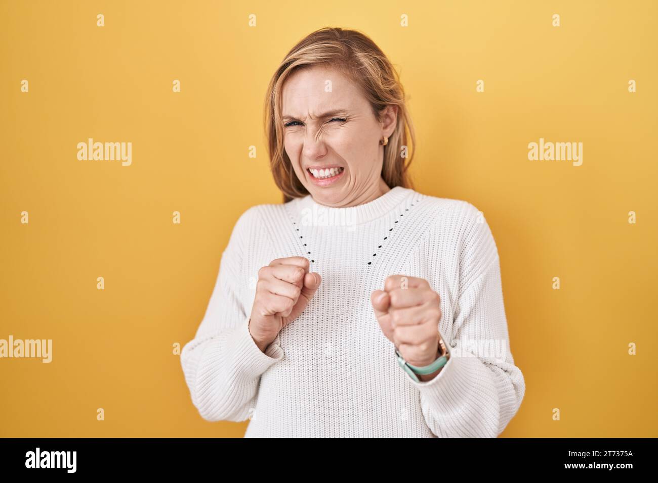 Young caucasian woman wearing white sweater over yellow background ...