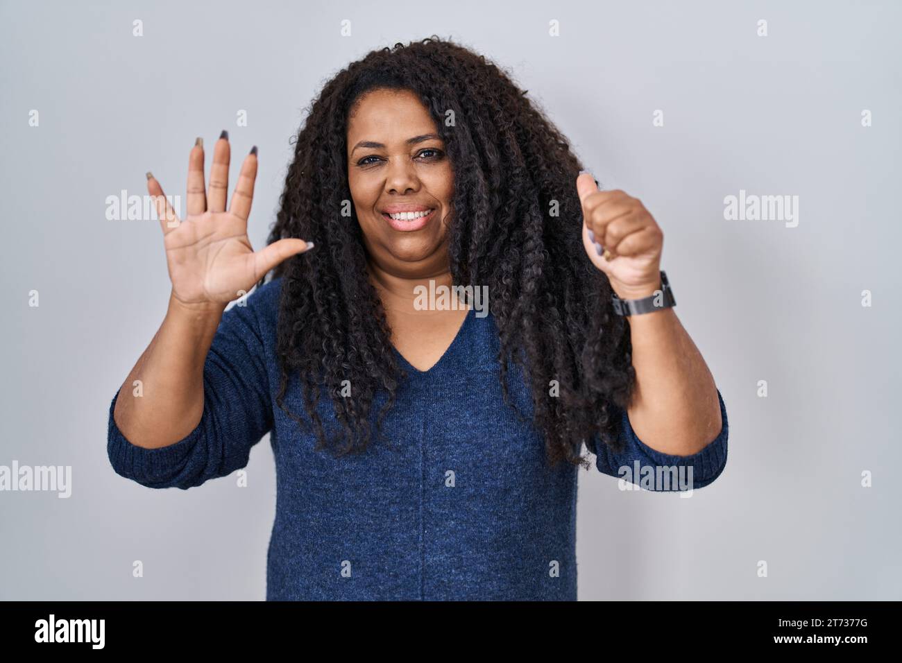 Plus size hispanic woman standing over white background showing and ...