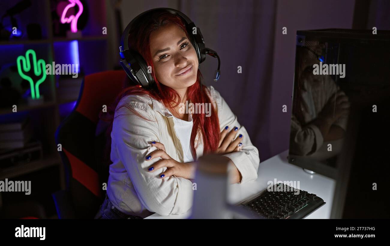 Relaxed young redhead woman streamer, arms crossed, flashes a smile ...