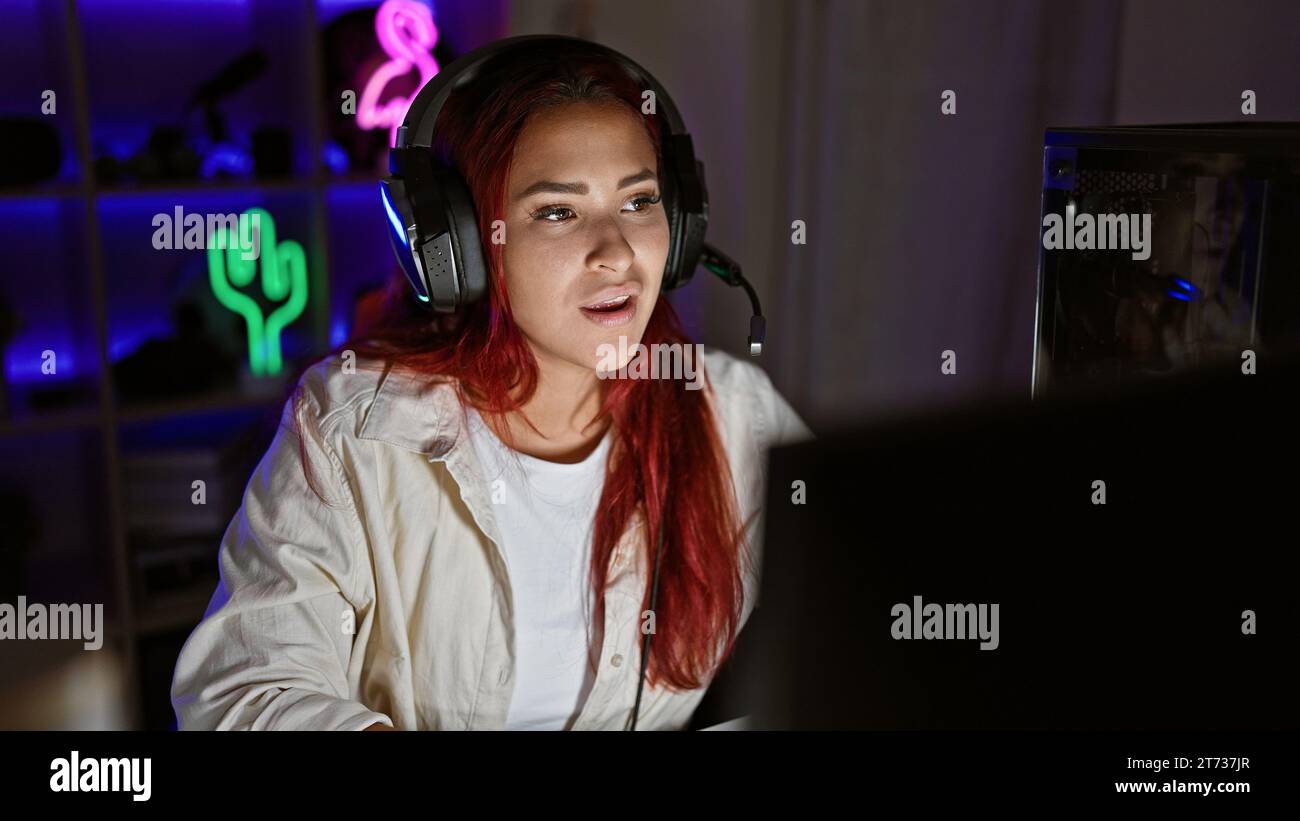 Focused young redhead woman streamer, engrossed in intense gaming ...