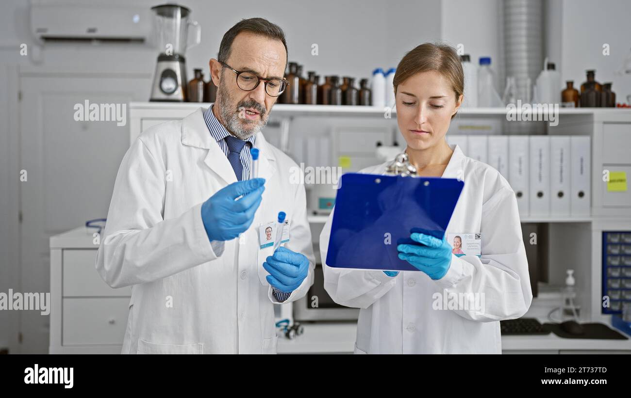 Two scientists holding test tube taking notes at laboratory Stock Photo ...
