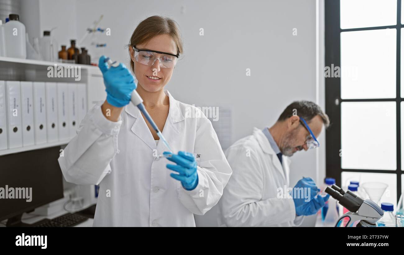 Two joyful lab mates, woman and man, pouring liquid into a sample ...