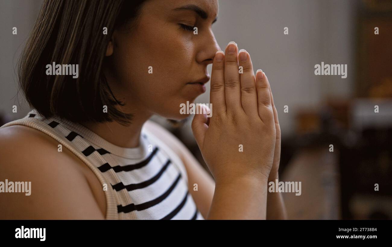 Young beautiful hispanic woman praying on a church bench at Augustinian ...