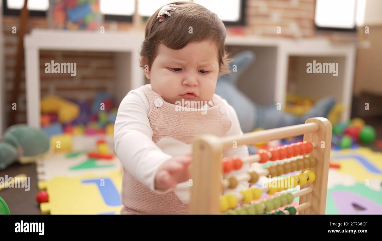 Adorable toddler playing with abacus sitting on floor at kindergarten ...