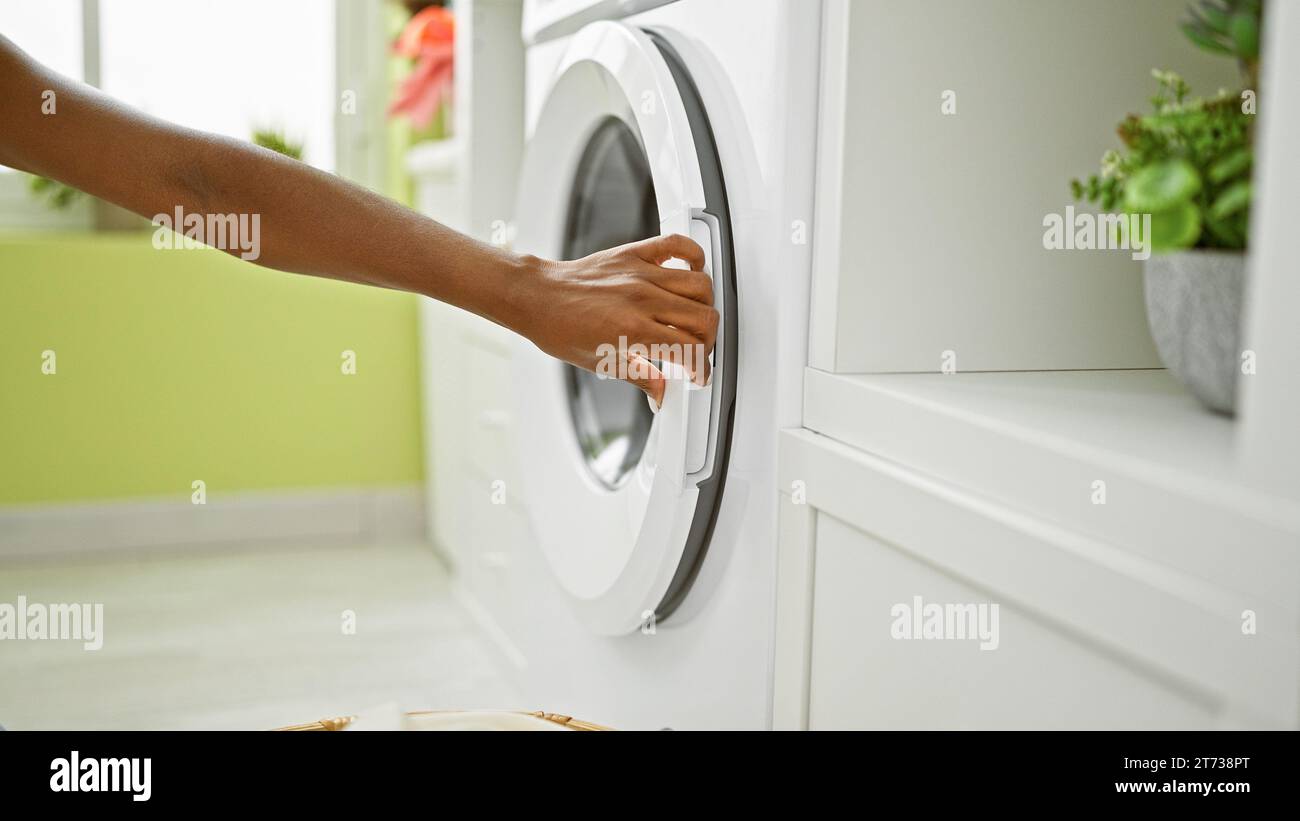African american woman opening washing machine door at laundry room ...