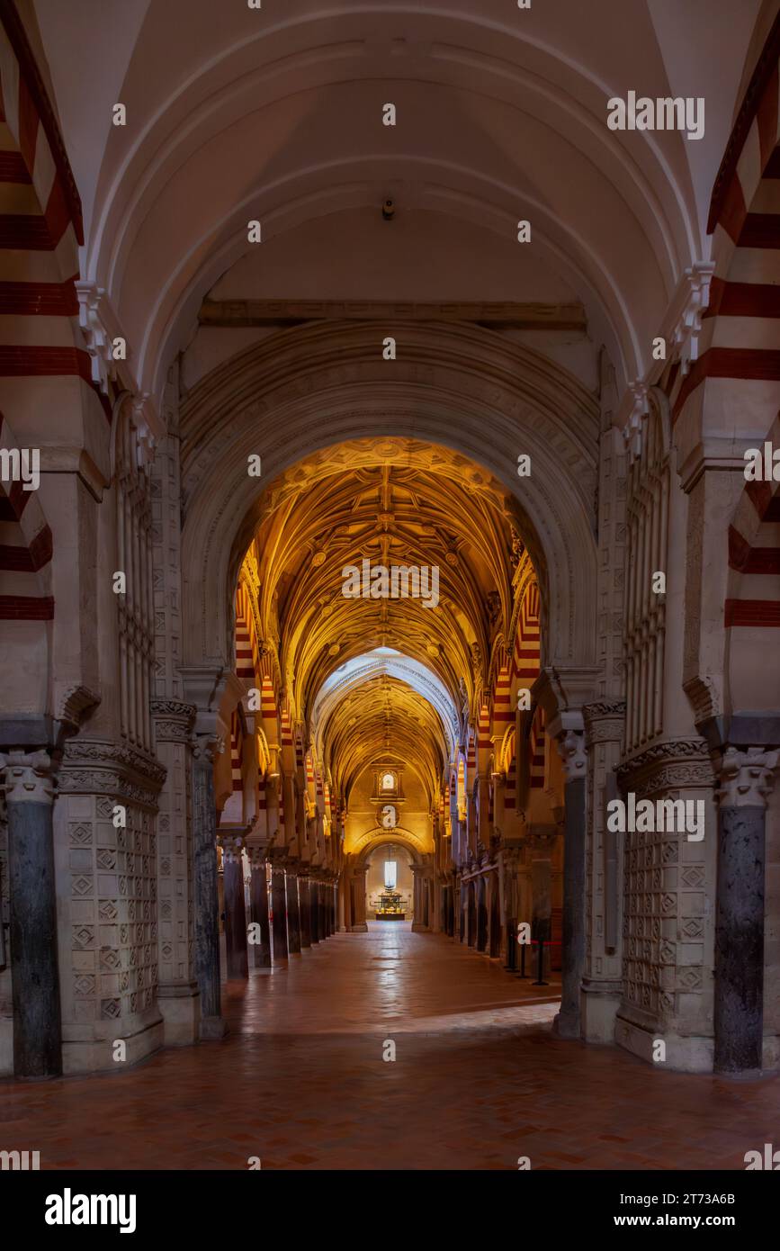 Corridor between pillars and decorated arches with views of a chapel in ...