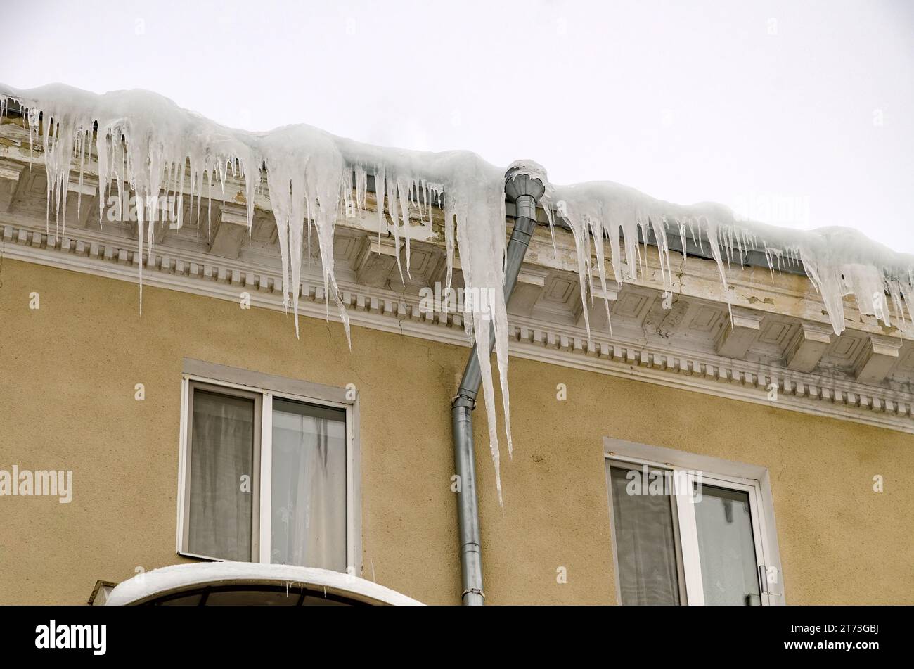 Huge pieces of ice hanging from the eaves of buildings threatening to ...