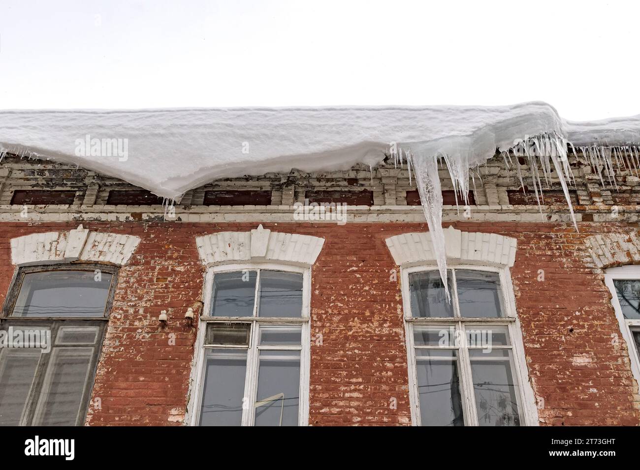 A huge ice block dangerously hangs down from the building’s charm ...