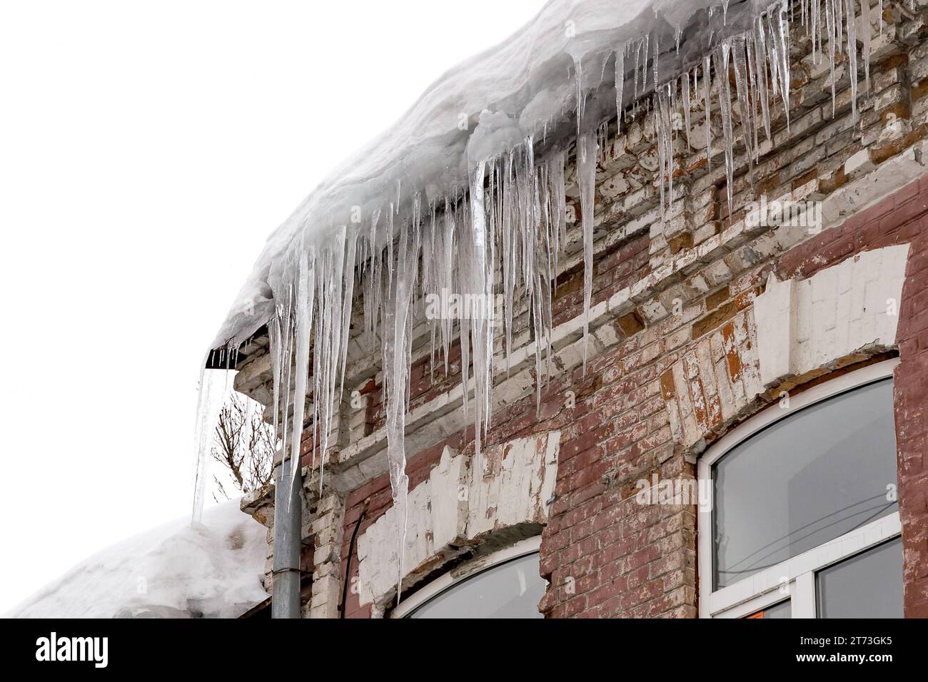 Huge icicles hang from the eaves of an old building, threatening to ...