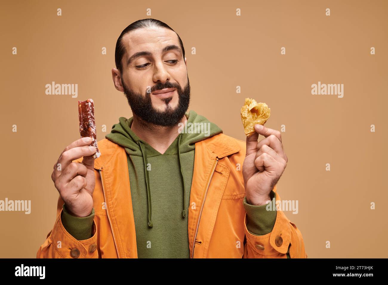 joyful bearded man smiling and holding baklava and cevizli sucuk on ...