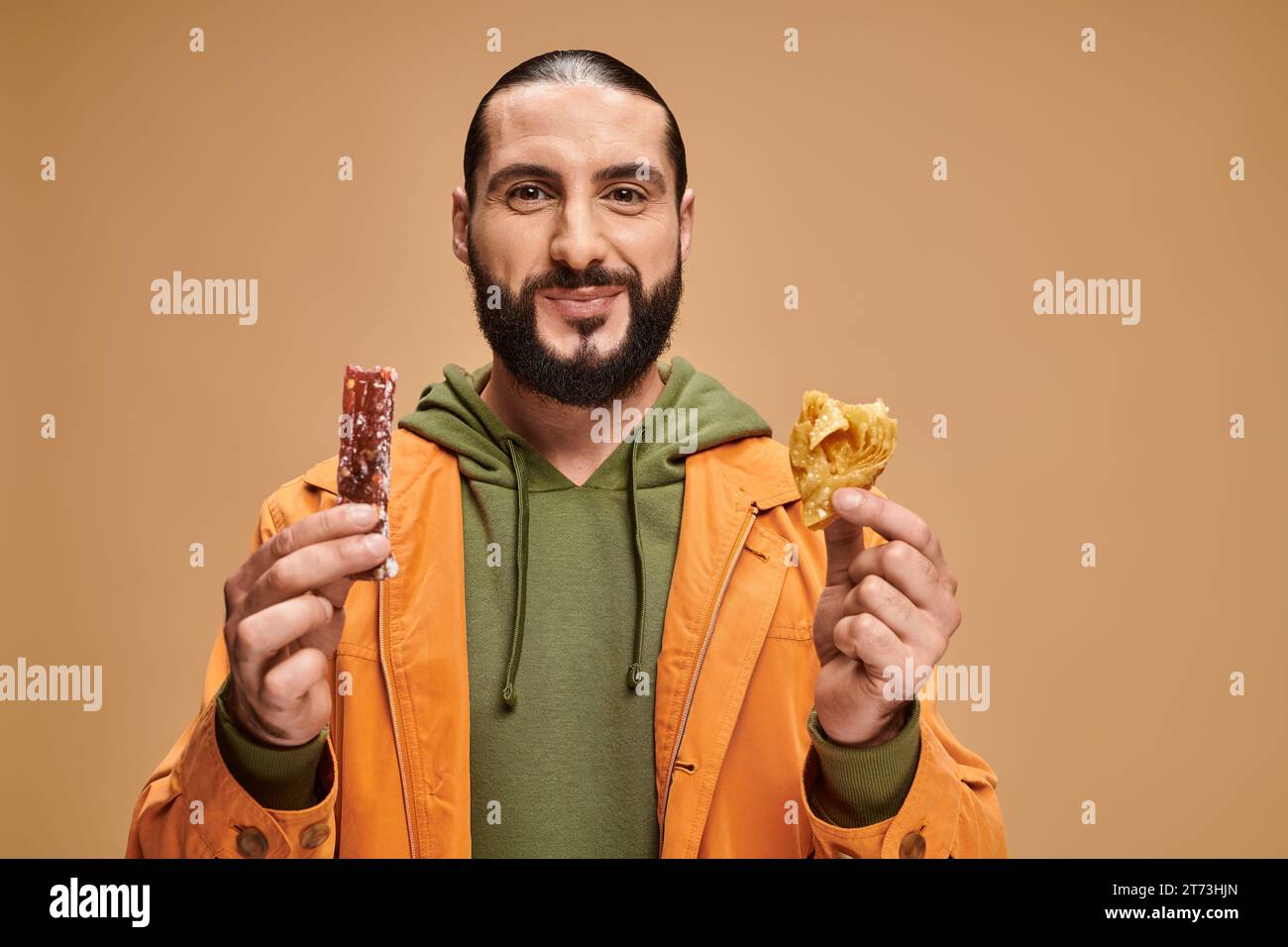 happy bearded man smiling and holding baklava and cevizli sucuk on ...