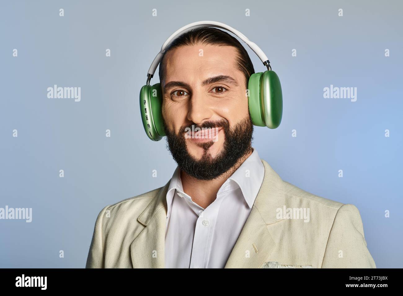 happy bearded man in elegant formal wear listening music in wireless ...