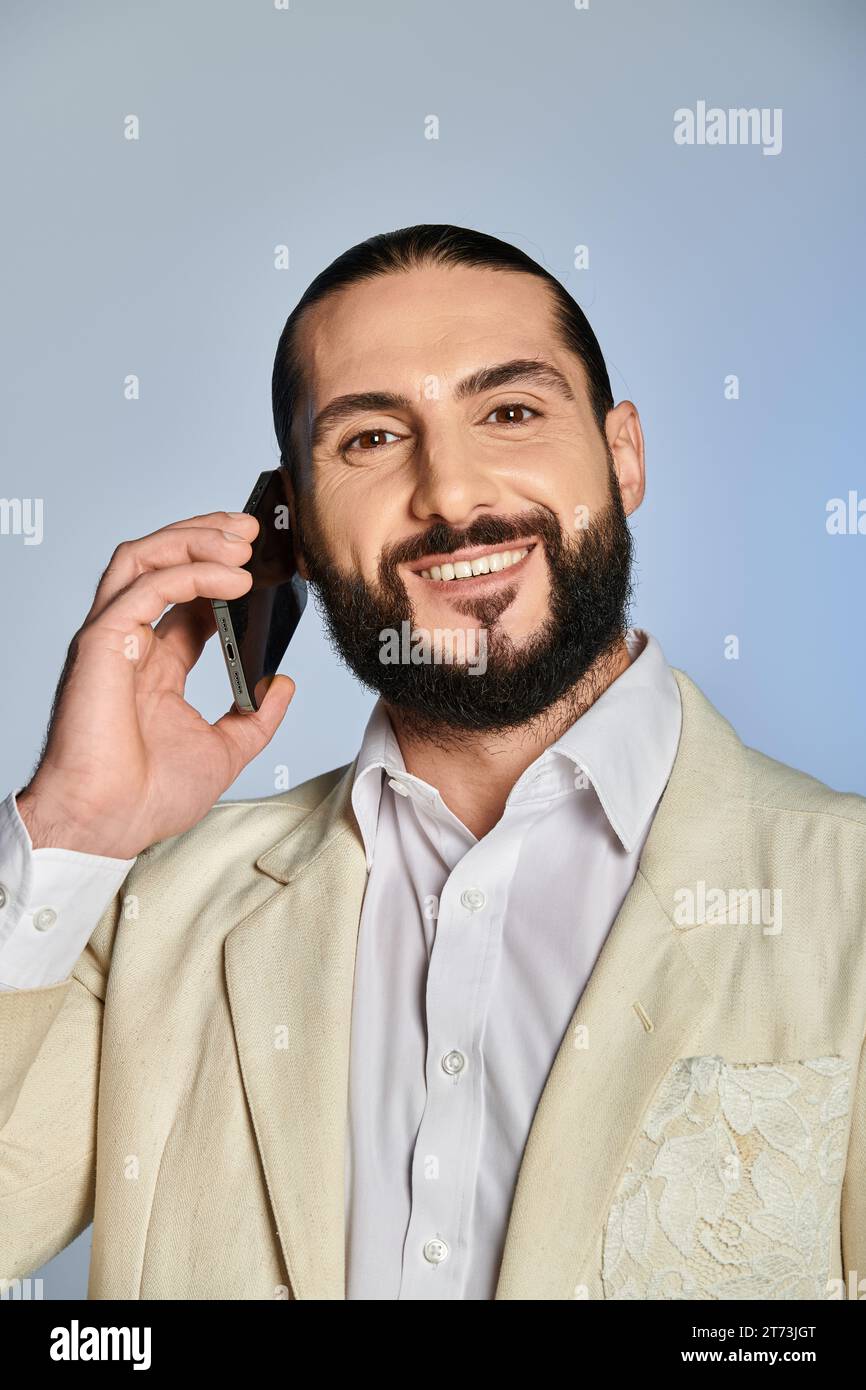 happy bearded arabic man in stylish formal wear talking on smartphone ...